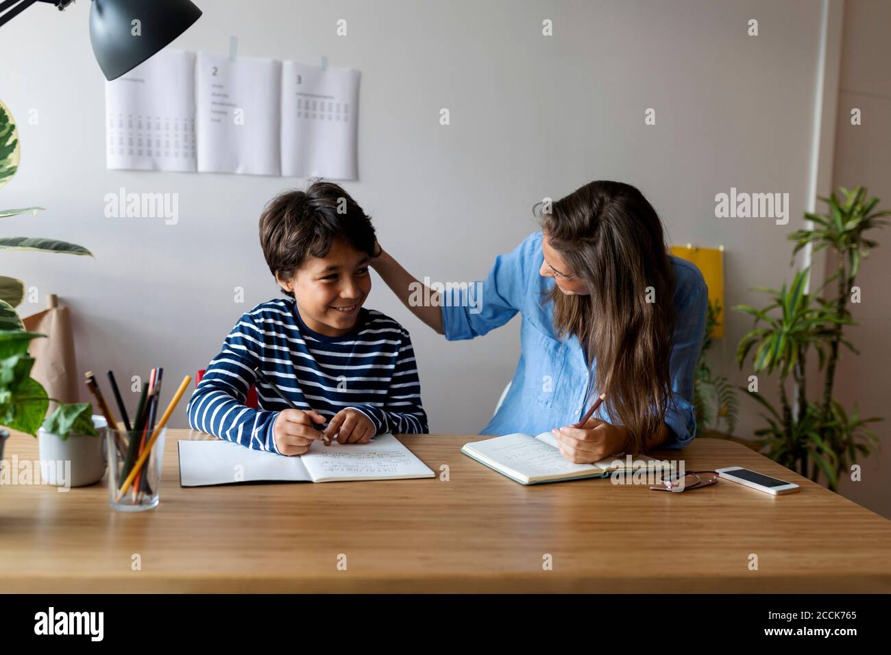 Female tutor talking with smiling boy while sitting at table Stock ...