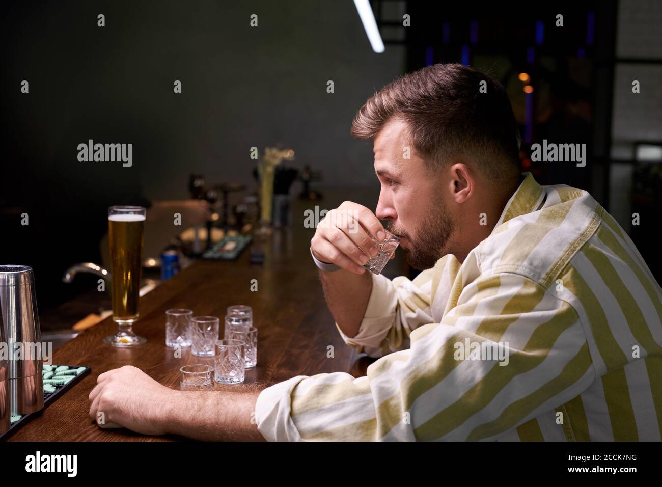 worried caucasian man sitting at bar with alcohol, young alcohol addict ...