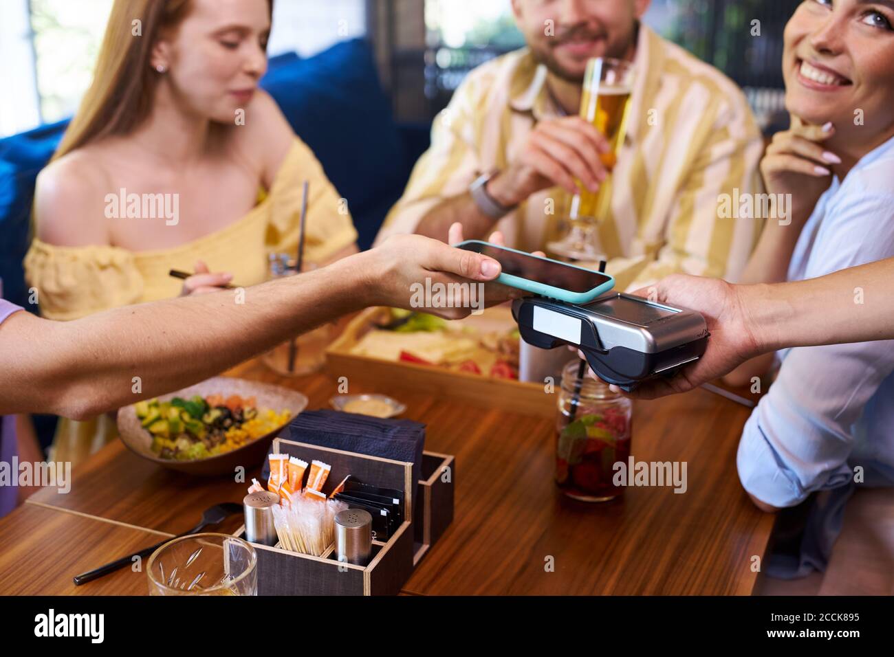 clients pay for meal via smartphone, in restaurant. contactless payment ...