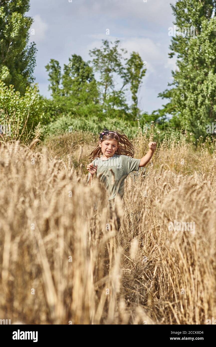 Girl running amidst crops in farm during sunny day Stock Photo - Alamy