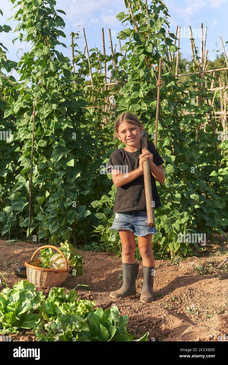 Girl standing with hoe in garden Stock Photo - Alamy