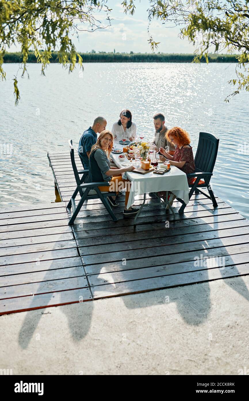 Friends having dinner on jetty at a lake Stock Photo - Alamy