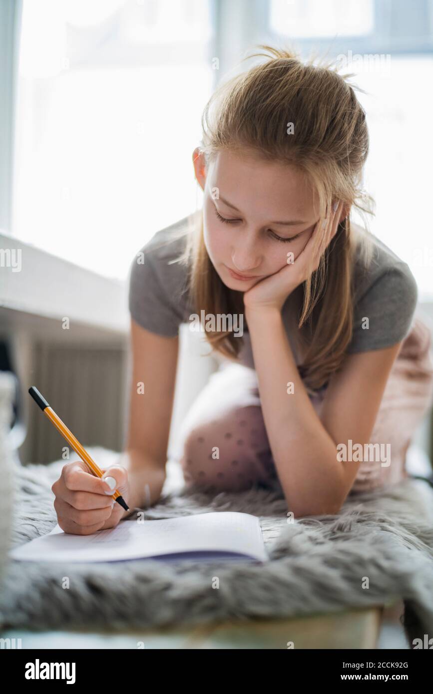 Girl learning at home, writing in exercise book Stock Photo - Alamy