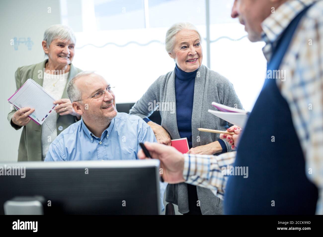 Active seniors attending computer course, watching instructor and ...