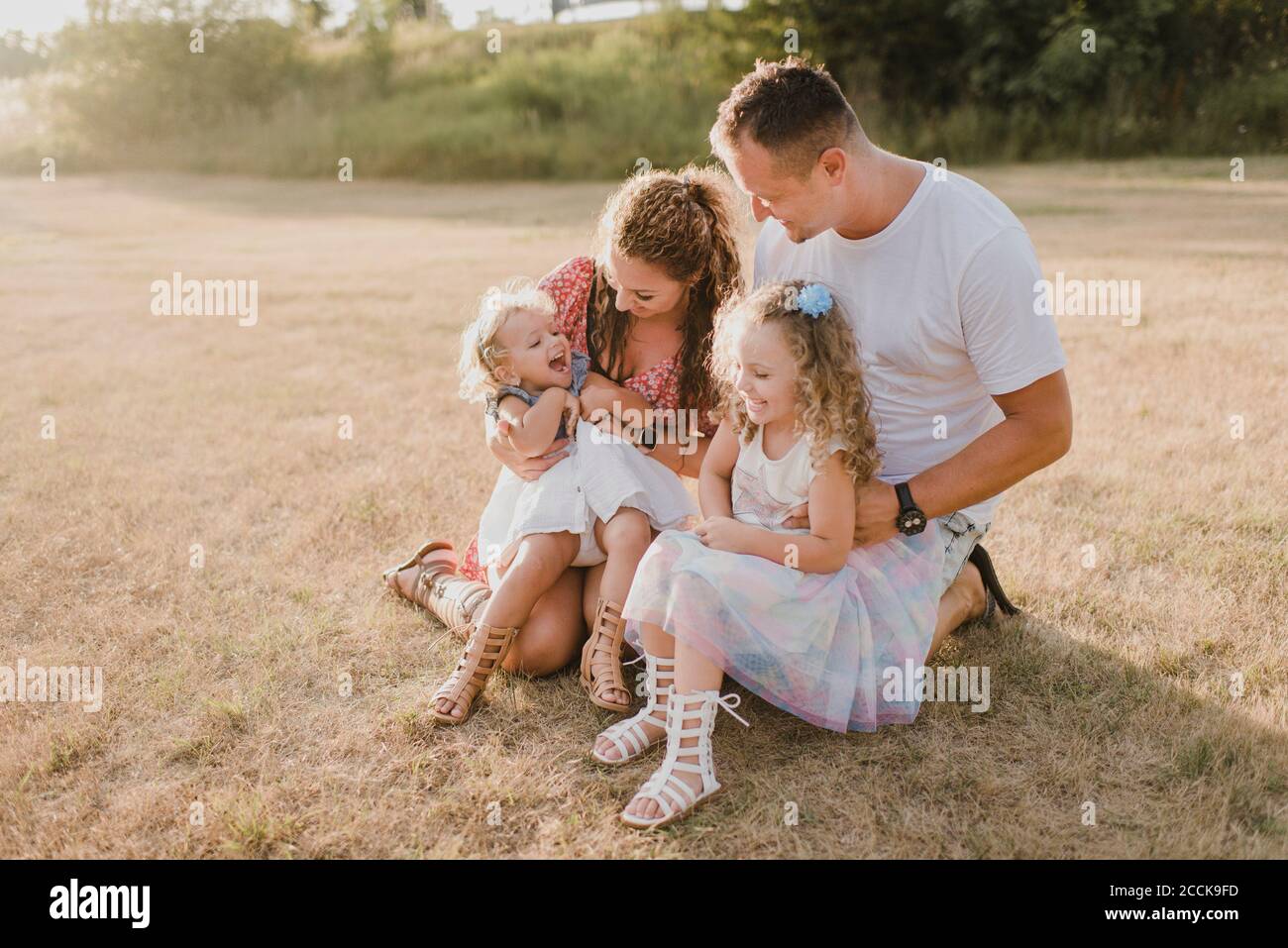 Happy parents with two daughters on a meadow Stock Photo - Alamy