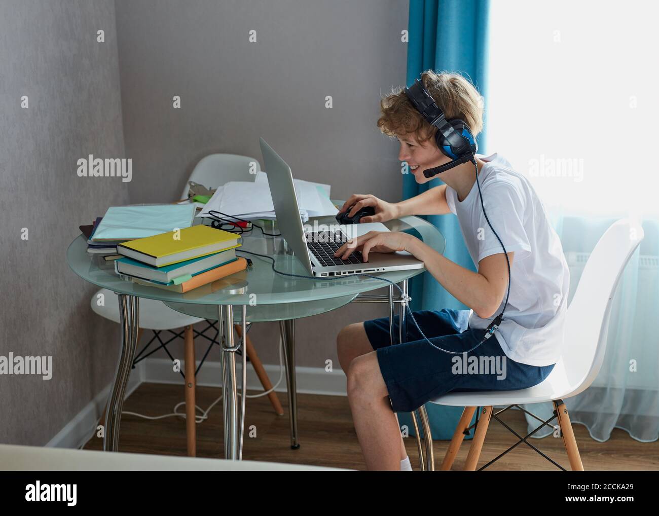 lazy teenager boy play computer games, sit in headphones, looking at ...