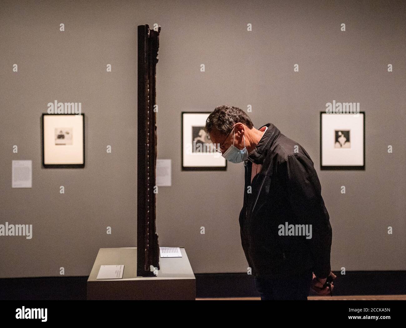 A man wearing face covering looks at a painting by Aubrey Beardsley ...