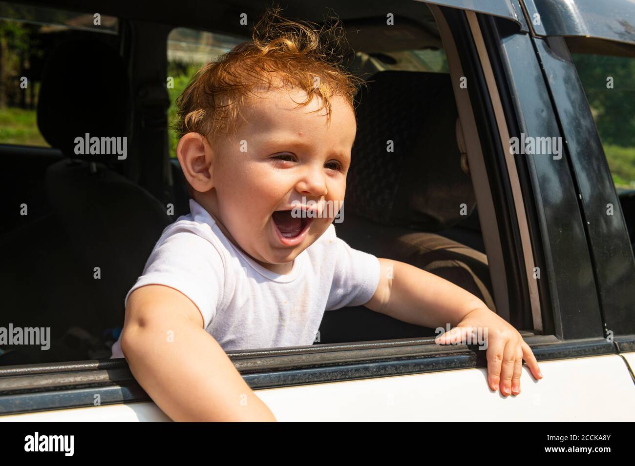 Smiling baby boy looking out of car window Stock Photo - Alamy