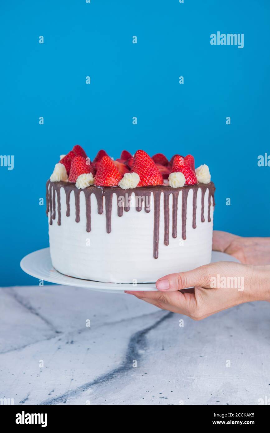 Hands holding cake with icing, chocolate and strawberries Stock Photo ...