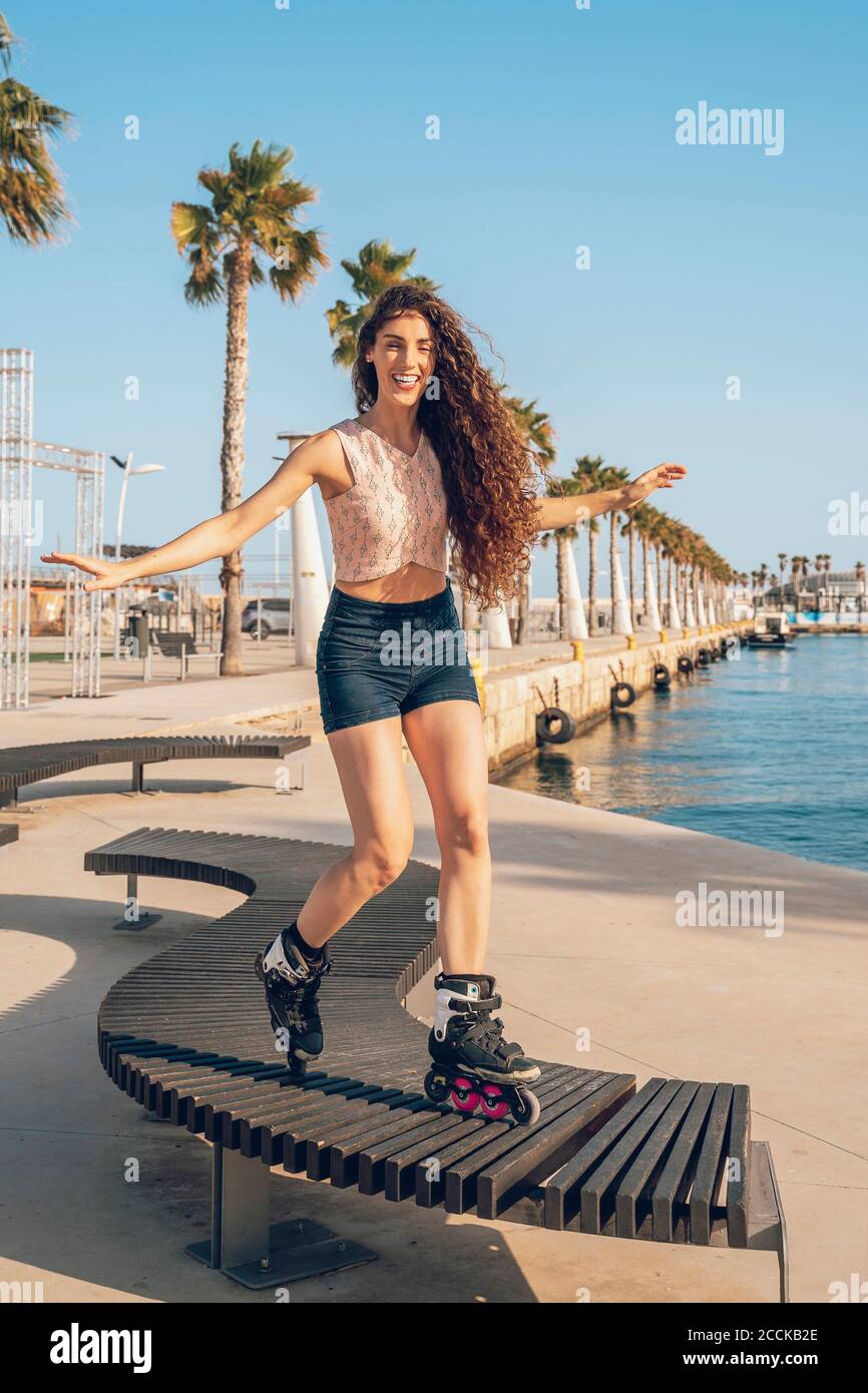 Young woman inline skating on bench Stock Photo - Alamy