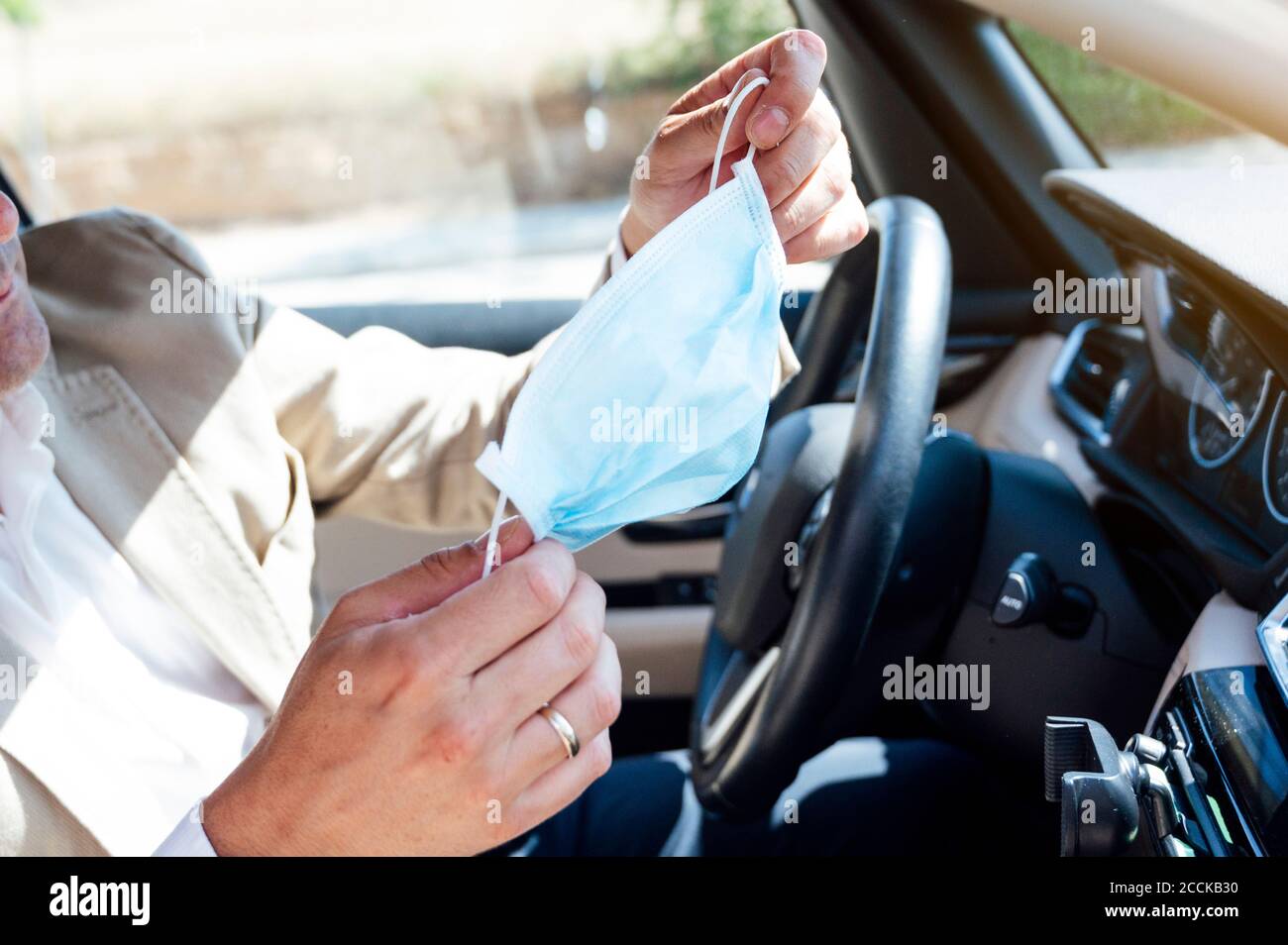 Man in car taking off his protective mask Stock Photo - Alamy
