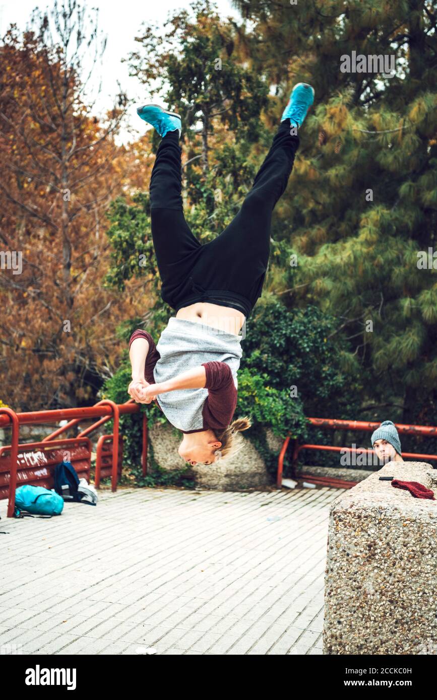 Young man looking at friend jumping upside down in park Stock Photo - Alamy