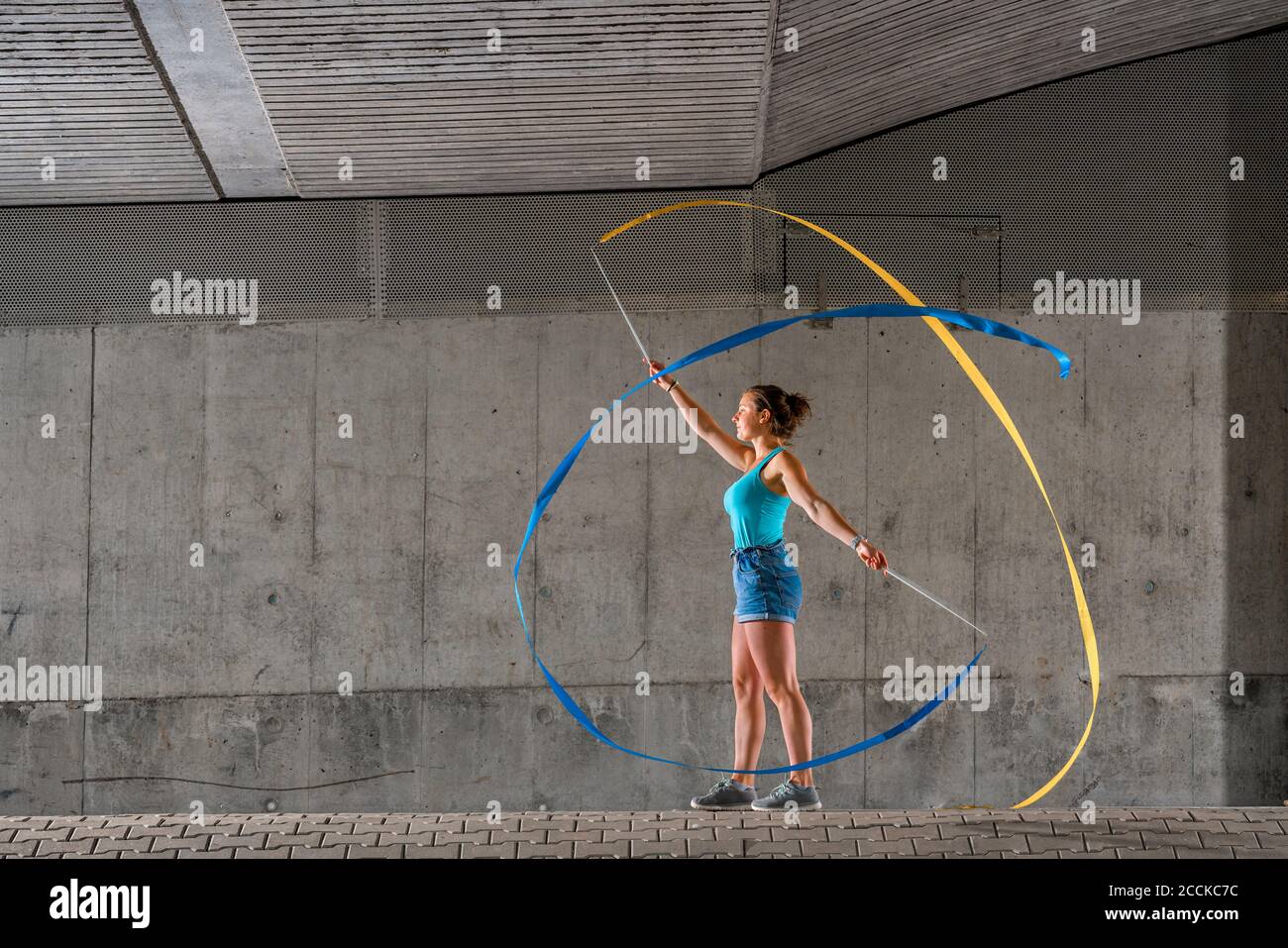 Young woman spinning ribbons while practicing rhythmic gymnastics ...