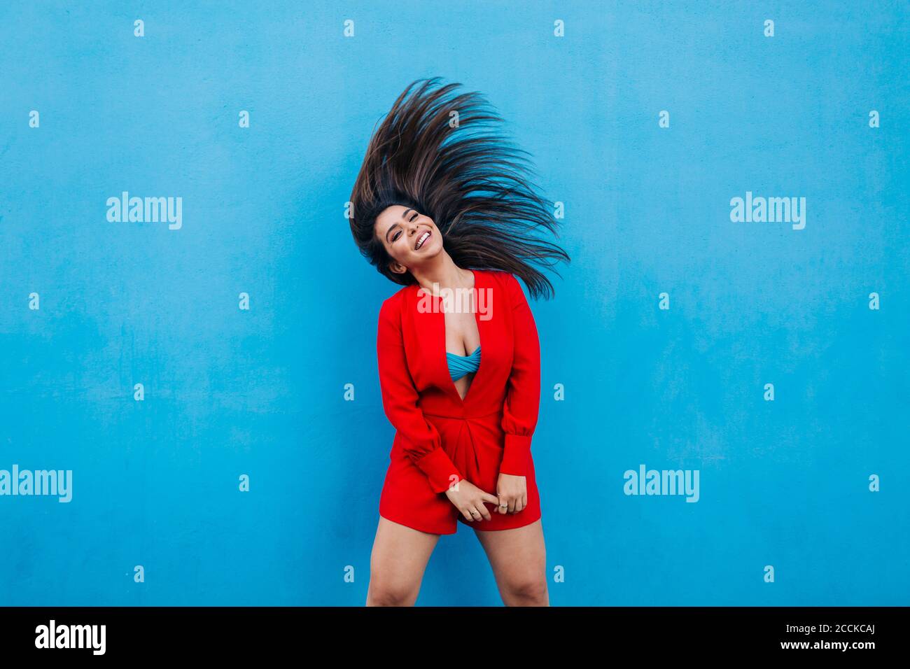 Laughing young woman shaking her head in front of blue wall Stock Photo ...