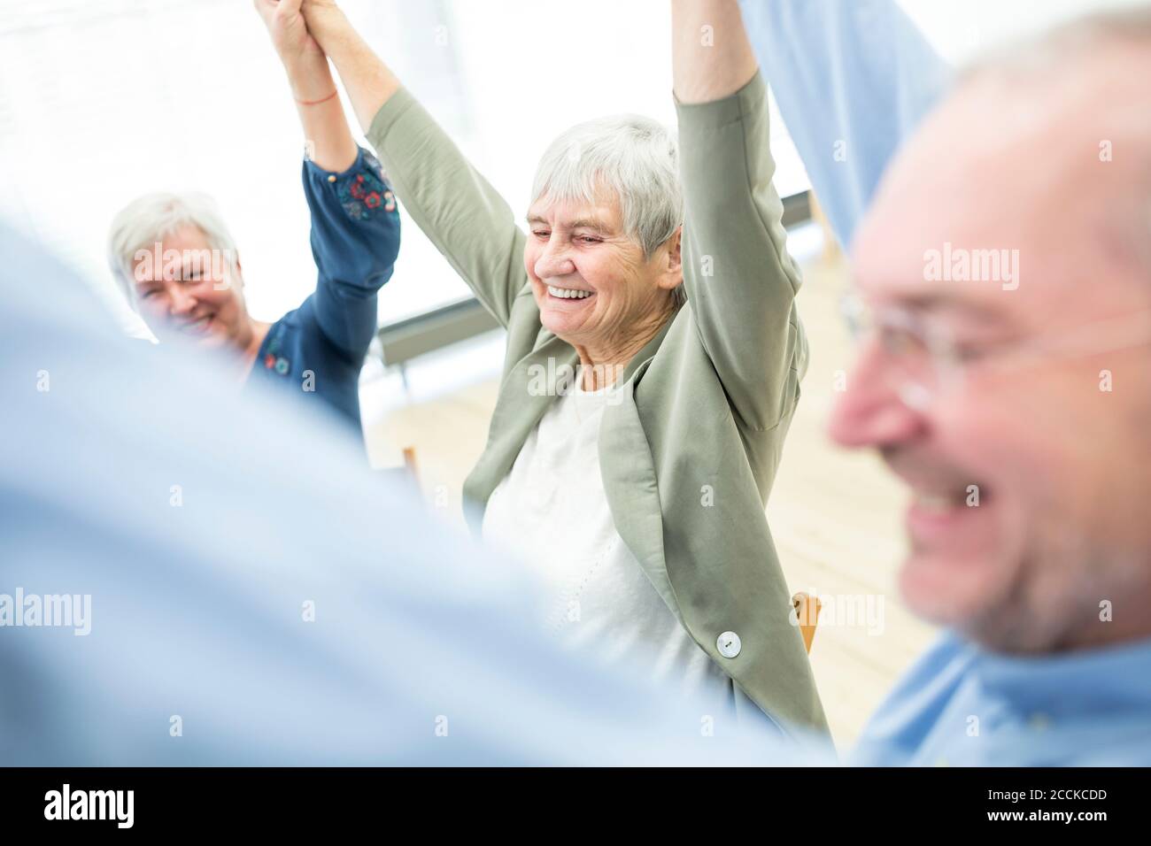Group of seniors practicing chair gymnastics with instructor in ...