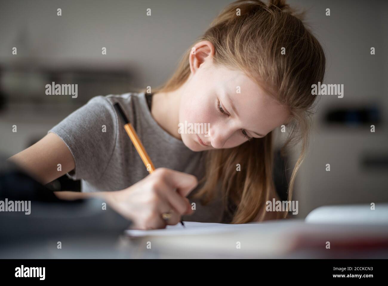 Girl learning at home, writing in exercise book Stock Photo - Alamy