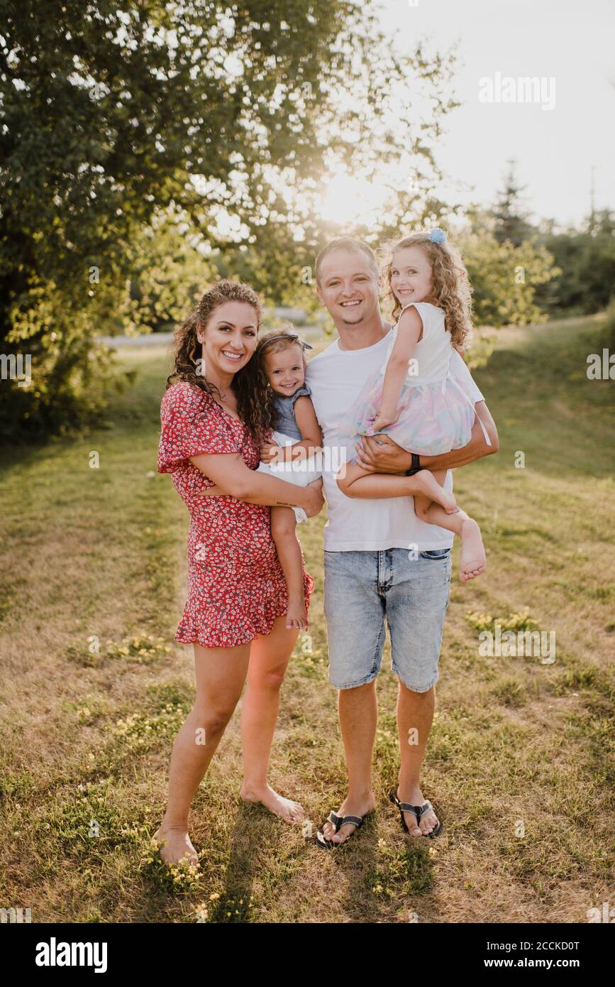 Portrait of happy parents with two daughters standing on a meadow Stock ...