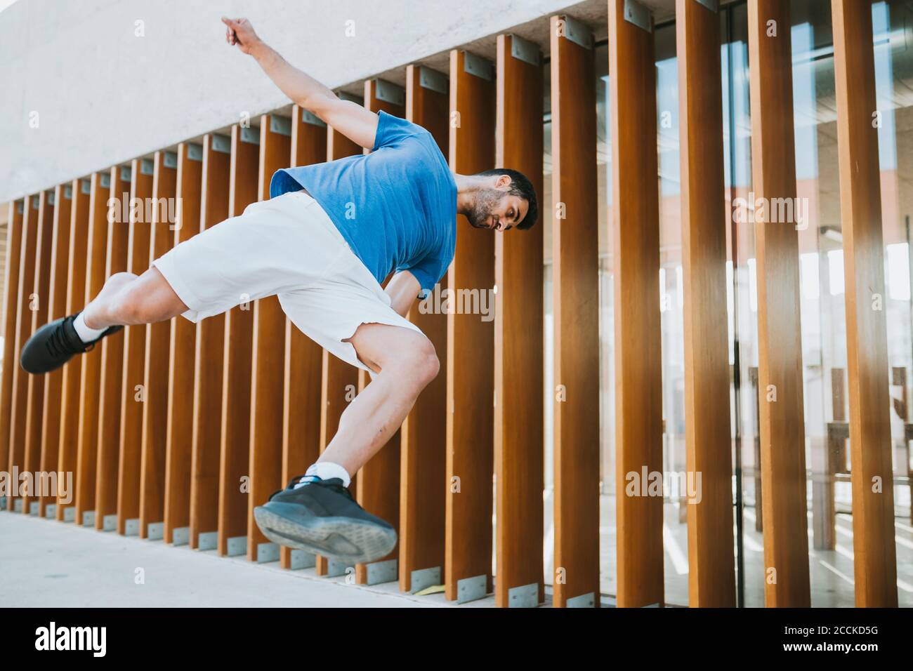 Young man performing stunt against built structure in city Stock Photo ...