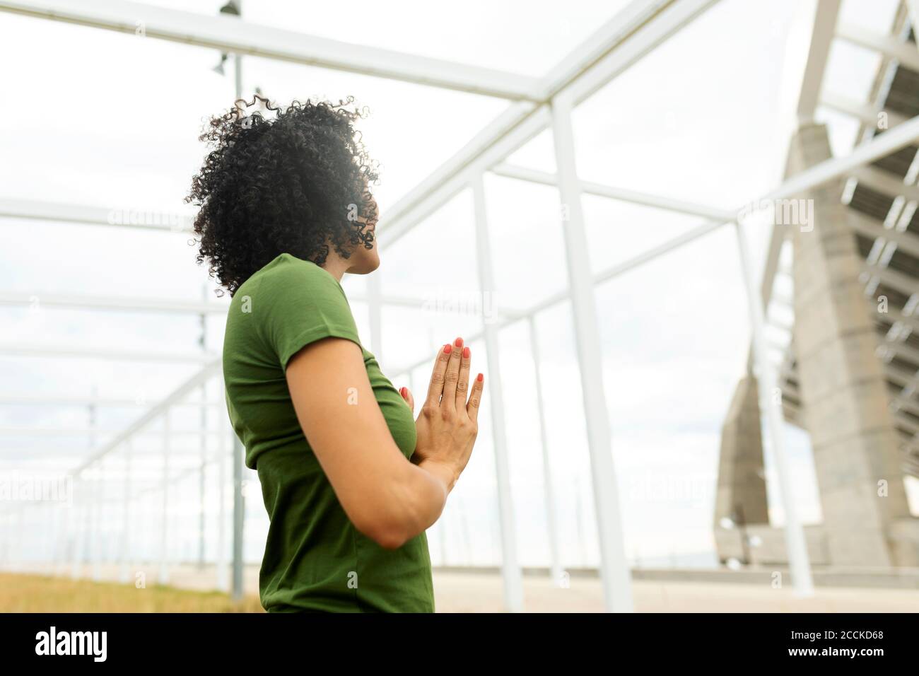 Mid adult woman meditating while standing against built structure in ...