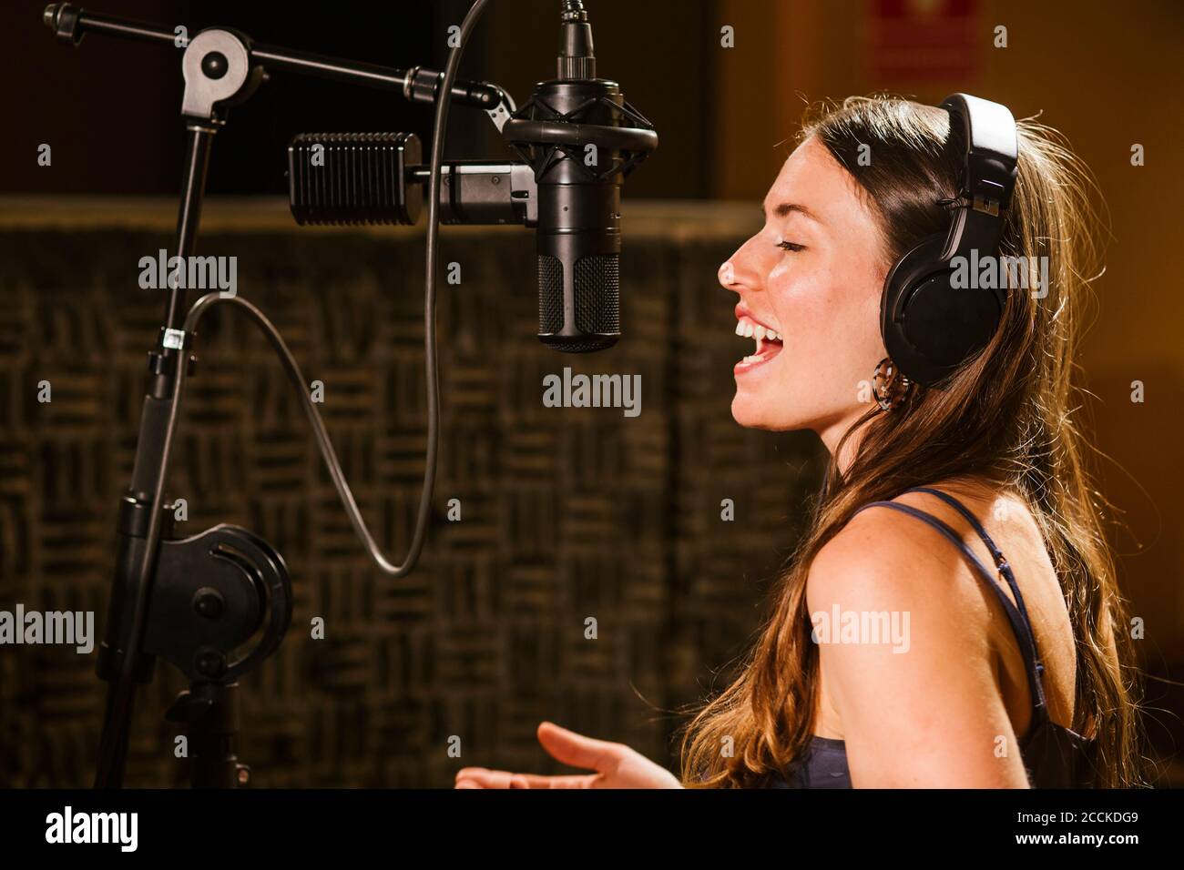Singer with headphones at microphone in recording studio Stock Photo ...