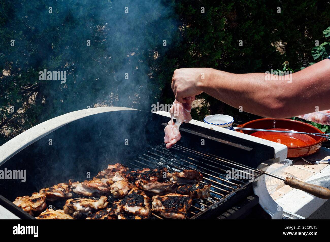 Hand of young man placing meat on barbecue grill in yard Stock Photo ...