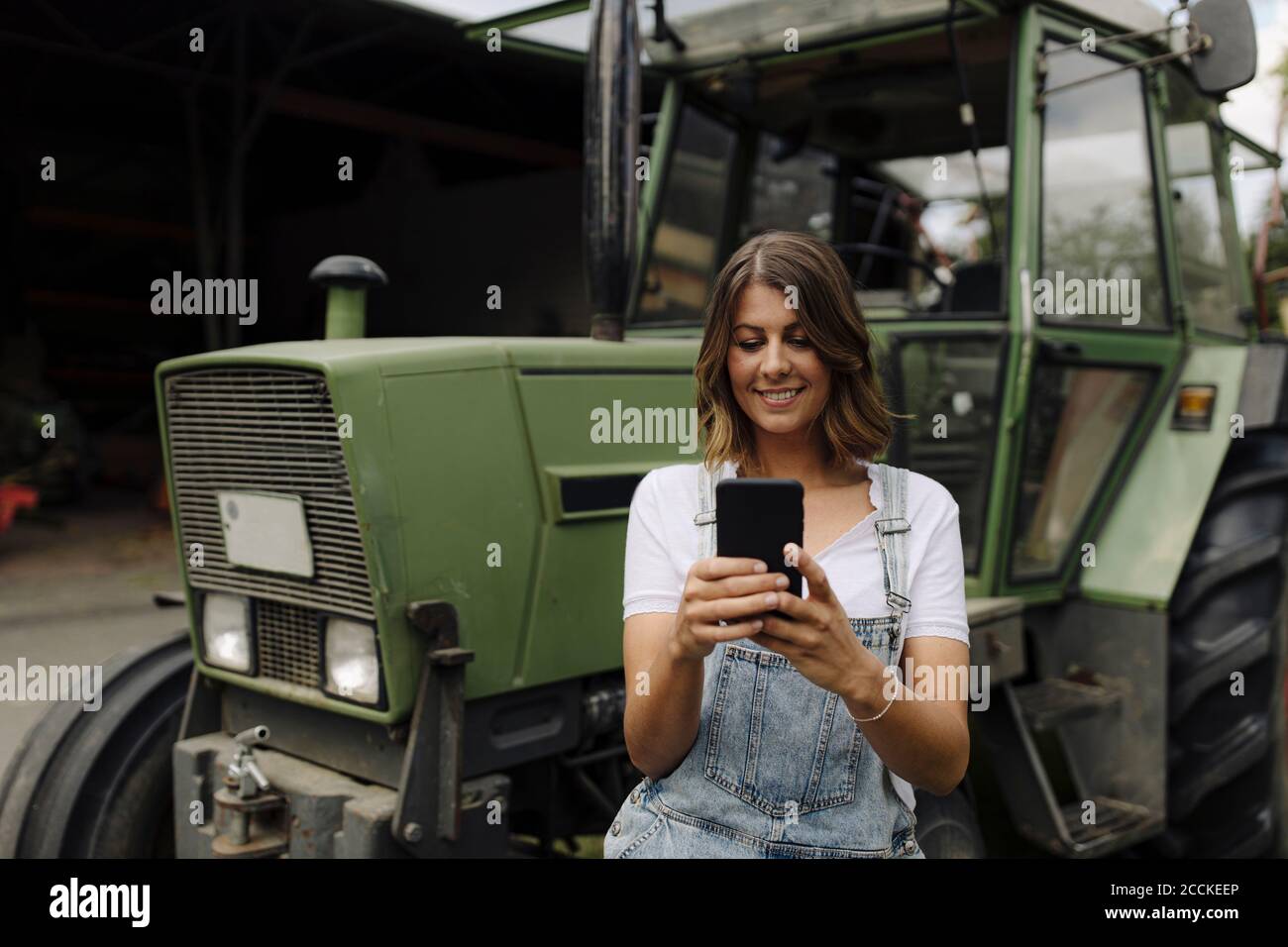 Young woman using mobile phone at a tractor on a farm Stock Photo - Alamy