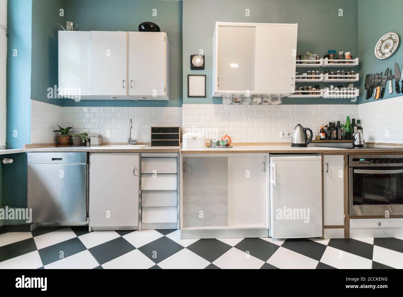 Tidy apartment kitchen with checkerboard floor Stock Photo - Alamy