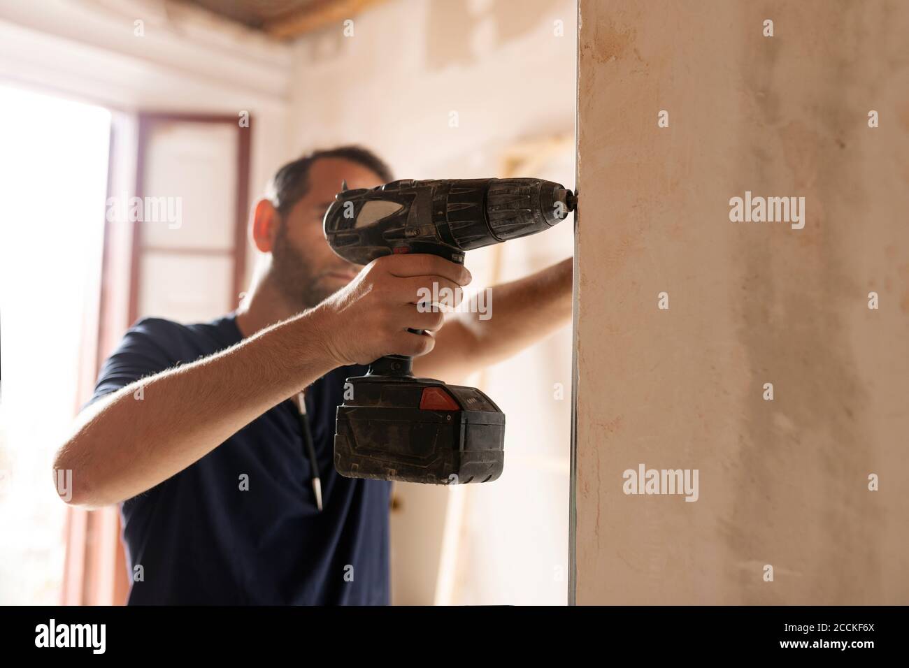 Construction worker using drill at a wall Stock Photo - Alamy