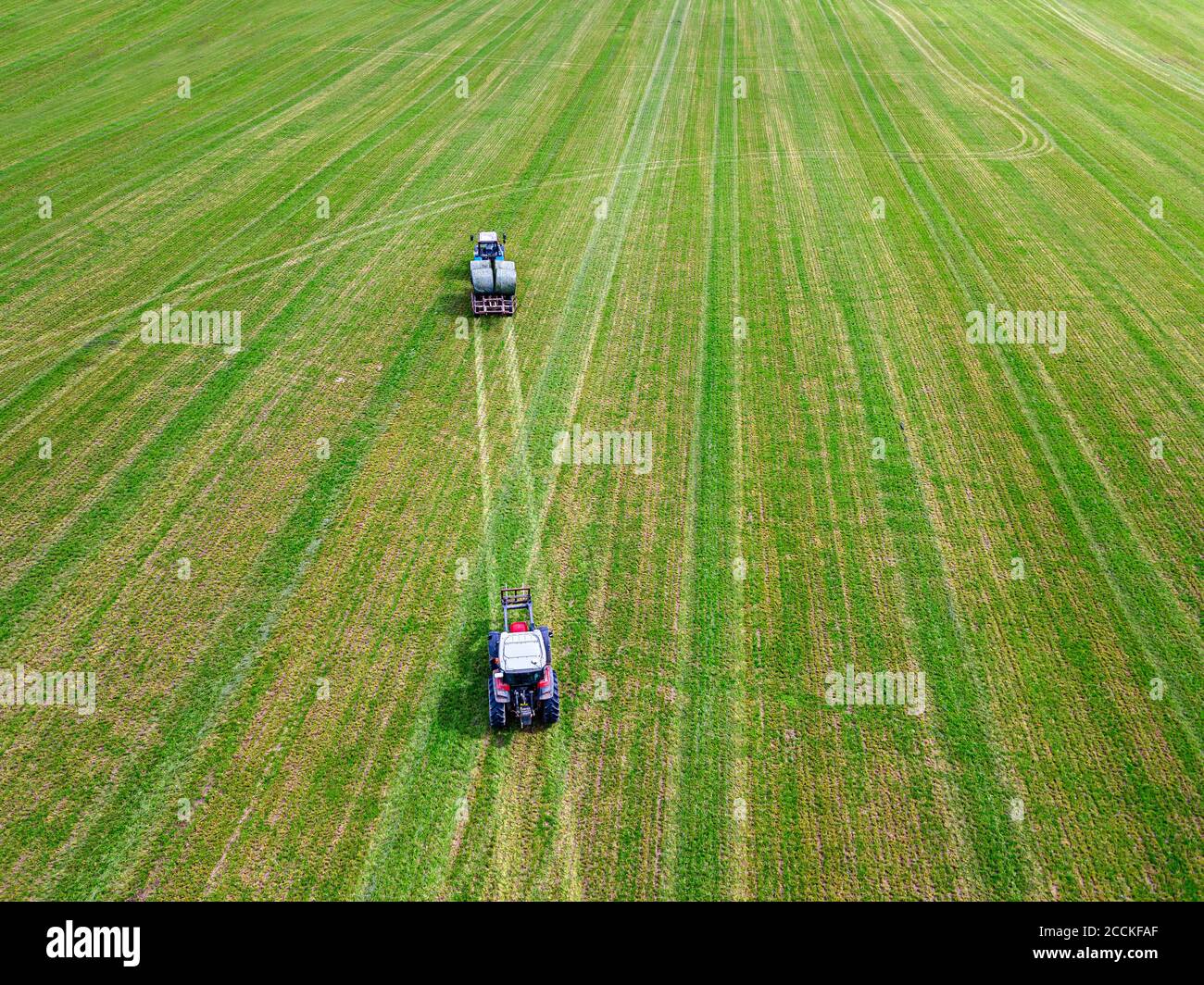 Aerial view of two tractors collecting hay bales in field Stock Photo ...