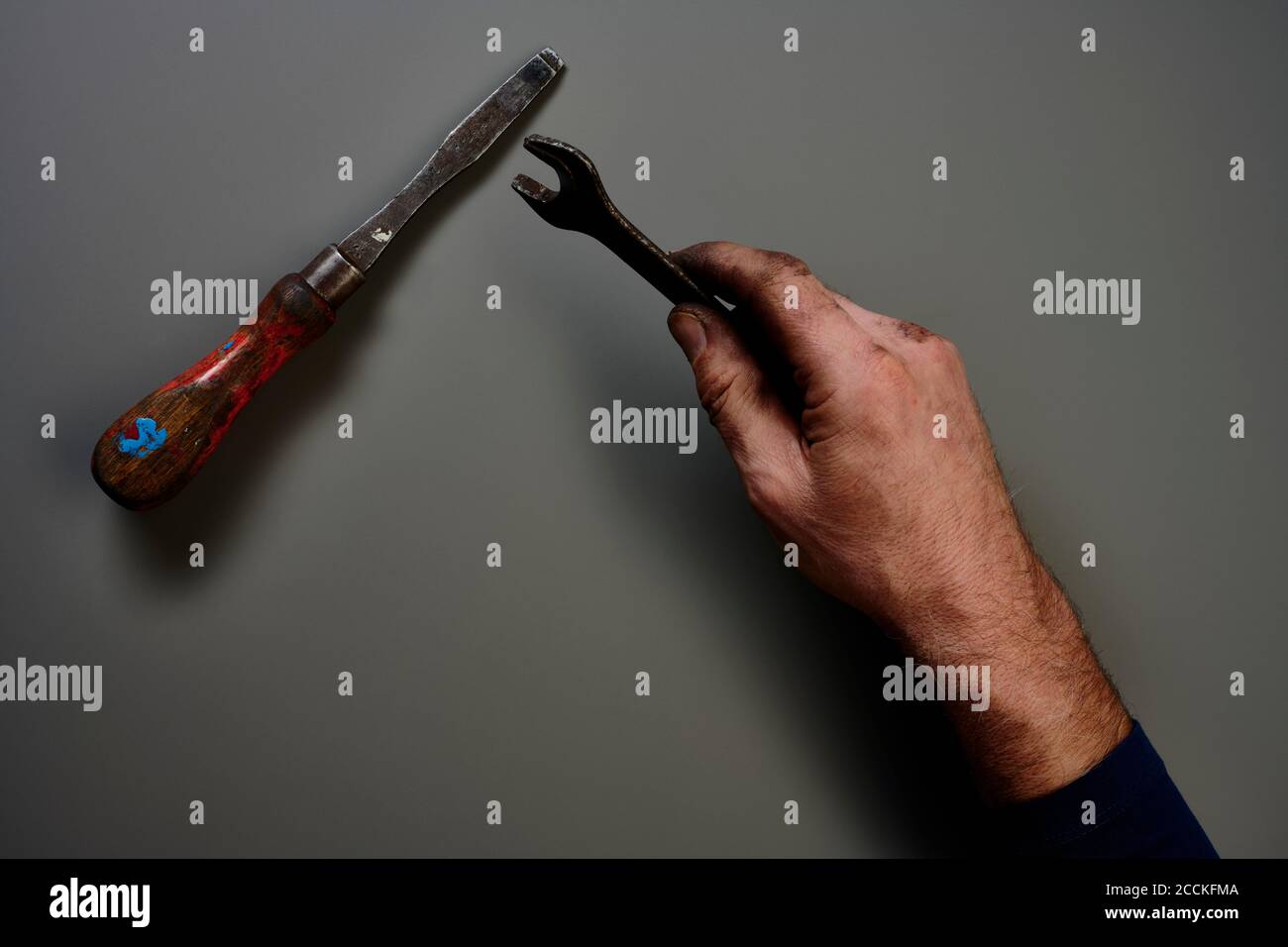 Top view of hand with tools in front of grey background Stock Photo - Alamy