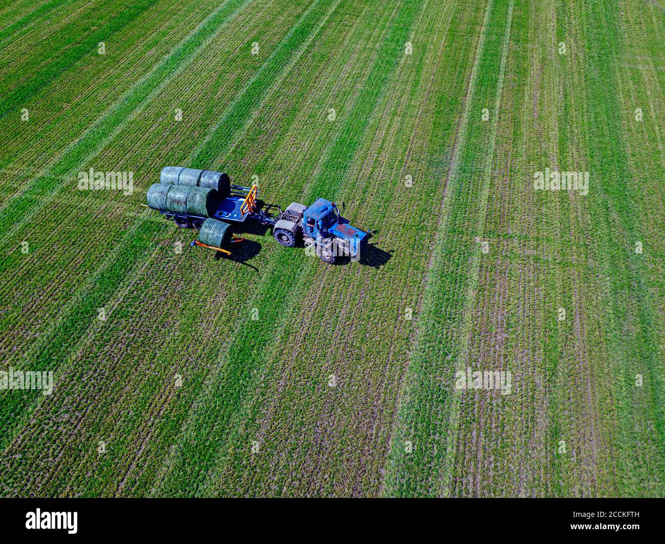 Aerial view of tractor collecting hay bales in field Stock Photo - Alamy