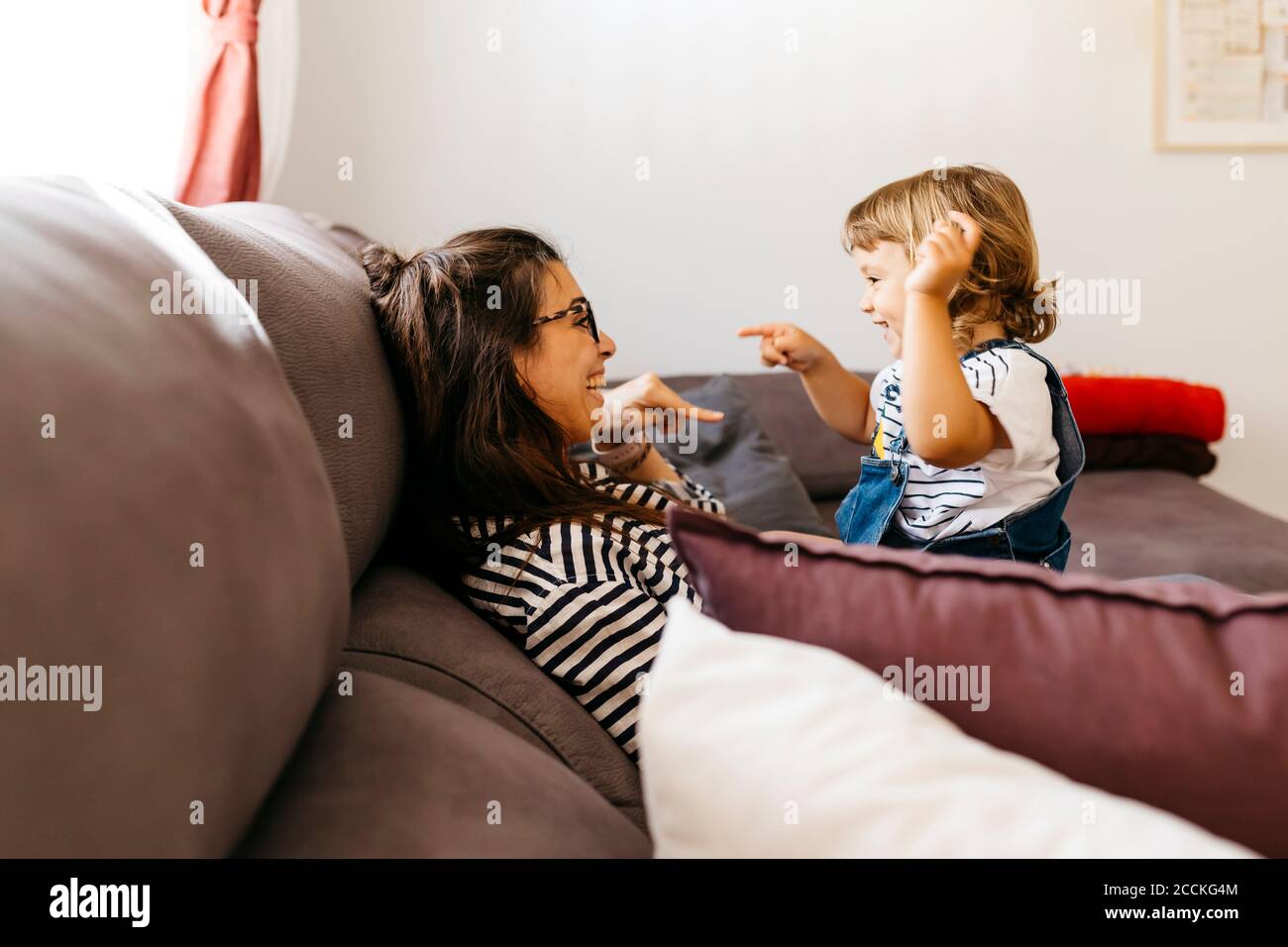 Happy mother and daughter talking while relaxing on sofa at home Stock ...