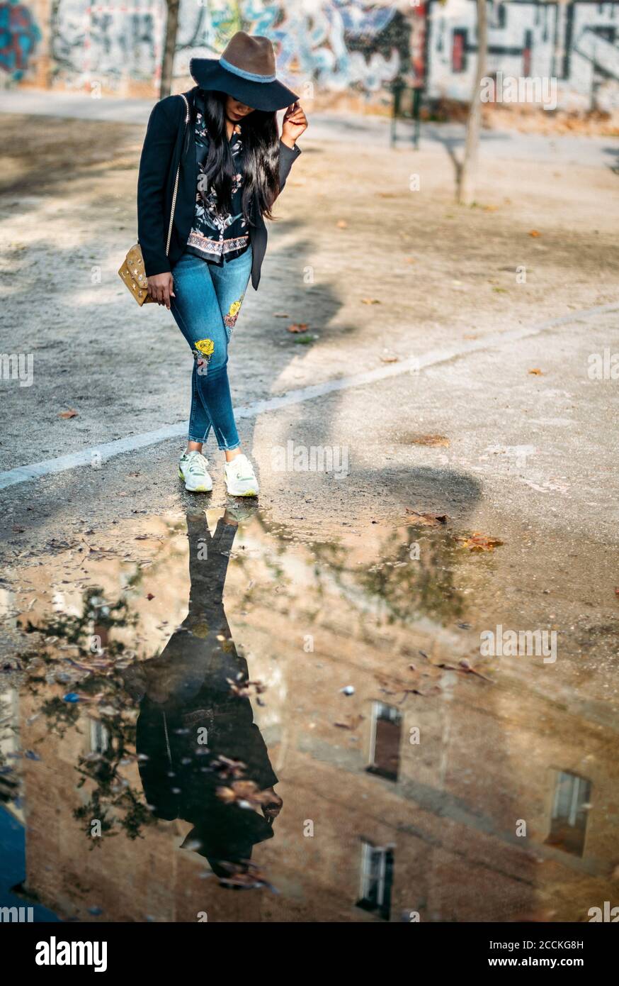 Woman standing by puddle with her reflection on road Stock Photo - Alamy