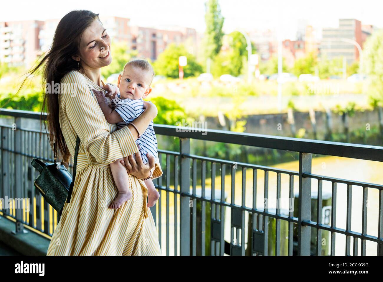 Mother holding her baby boy on a bridge Stock Photo - Alamy