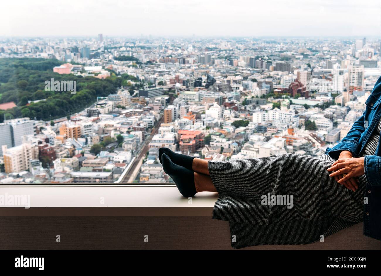 Japan, Tokyo, Woman sitting by window overlooking city Stock Photo - Alamy
