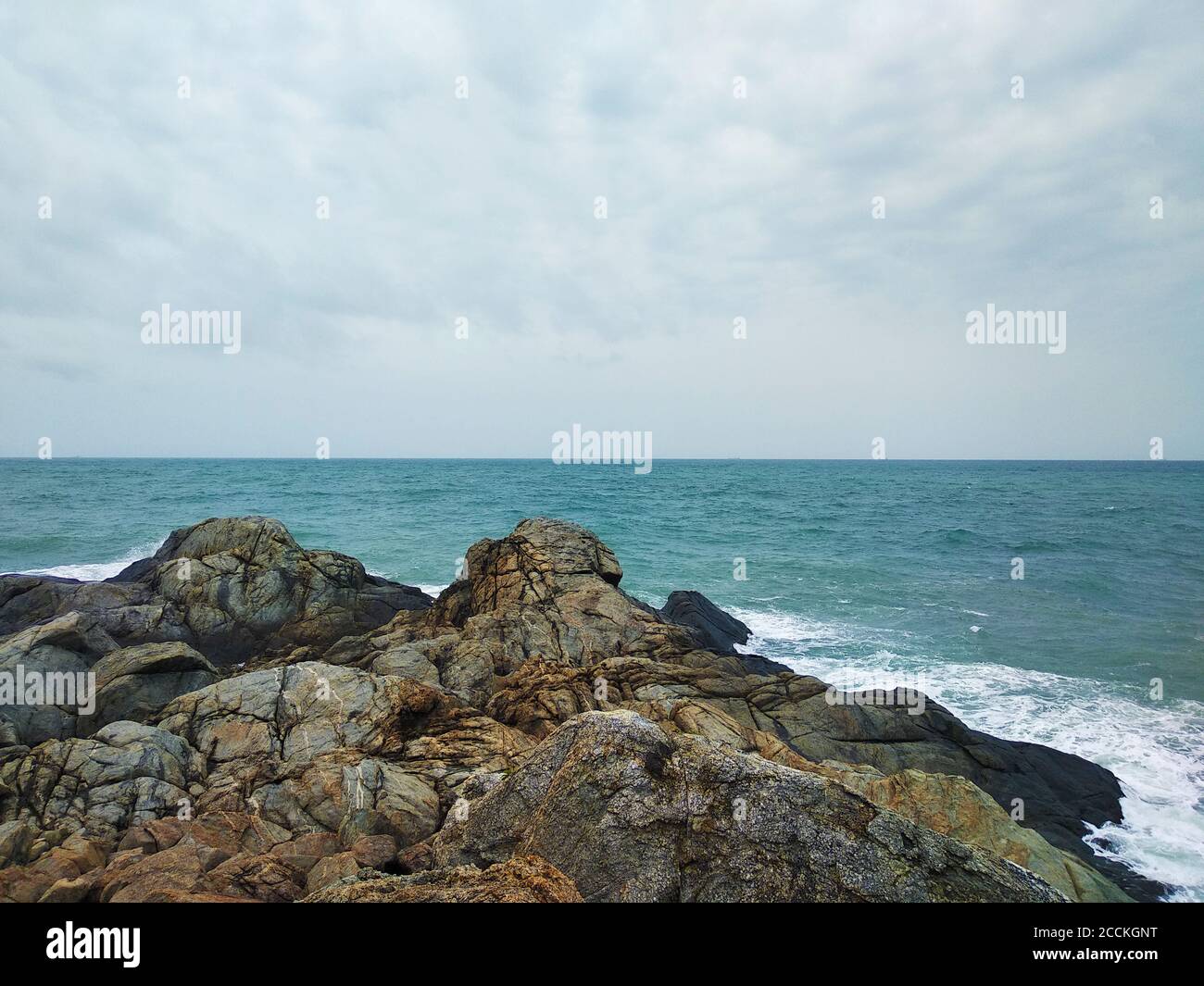 colorful brown rocks on the blue sea shore in cloudy day in Sanya of ...
