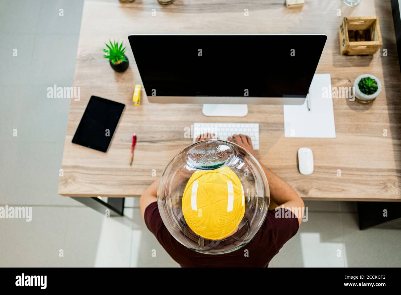 Businessman wearing fishbowl in head while using computer in modern ...