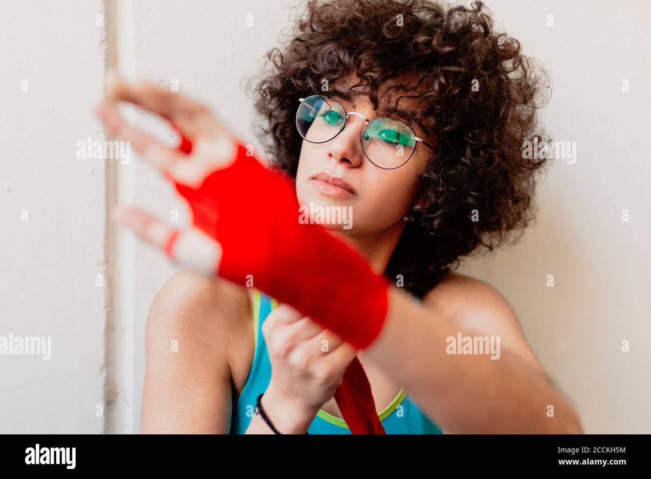 Close-up of female boxer with afro hair wrapping red bandage on hand in ...