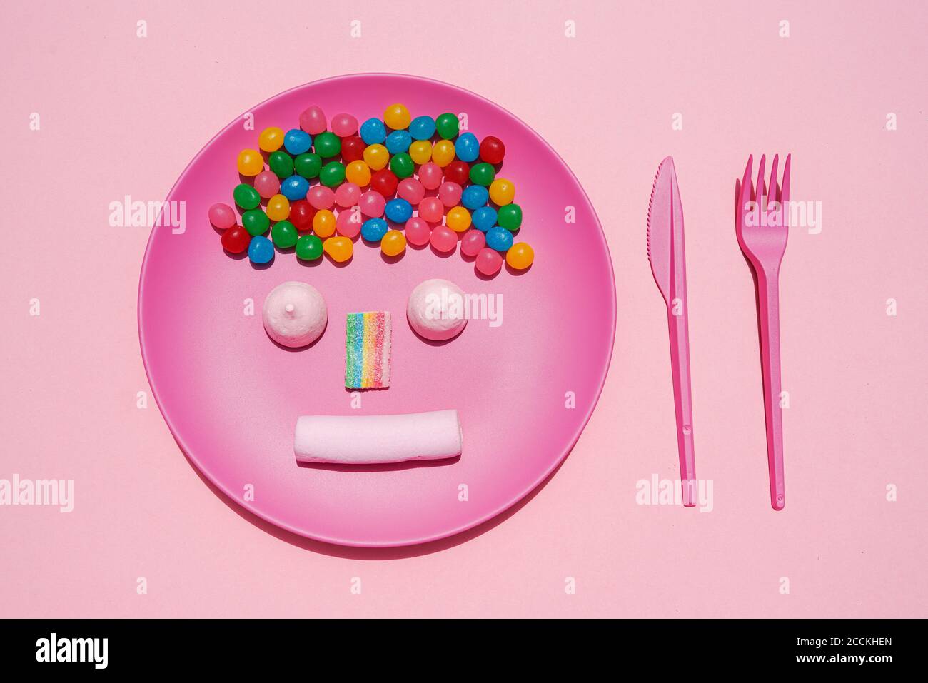 Studio shot of plastic plate with colorful candies and anthropomorphic ...