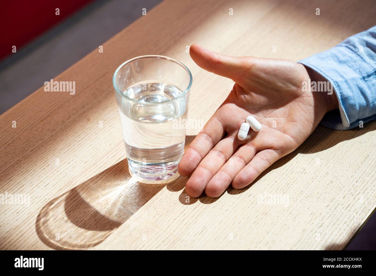 Hand with pills and water glass Stock Photo - Alamy