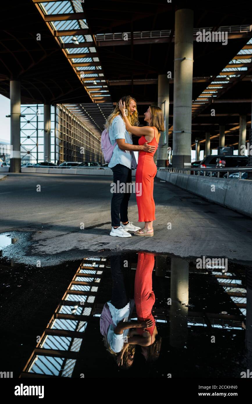 Couple standing face to face by reflection on puddle in city Stock ...