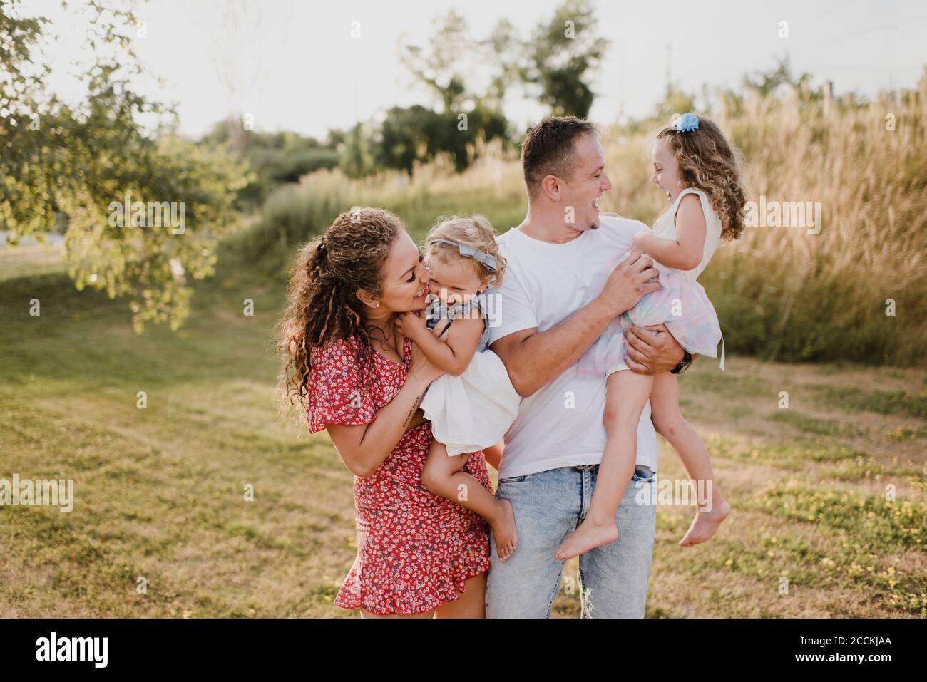 Happy parents with two daughters on a meadow Stock Photo - Alamy