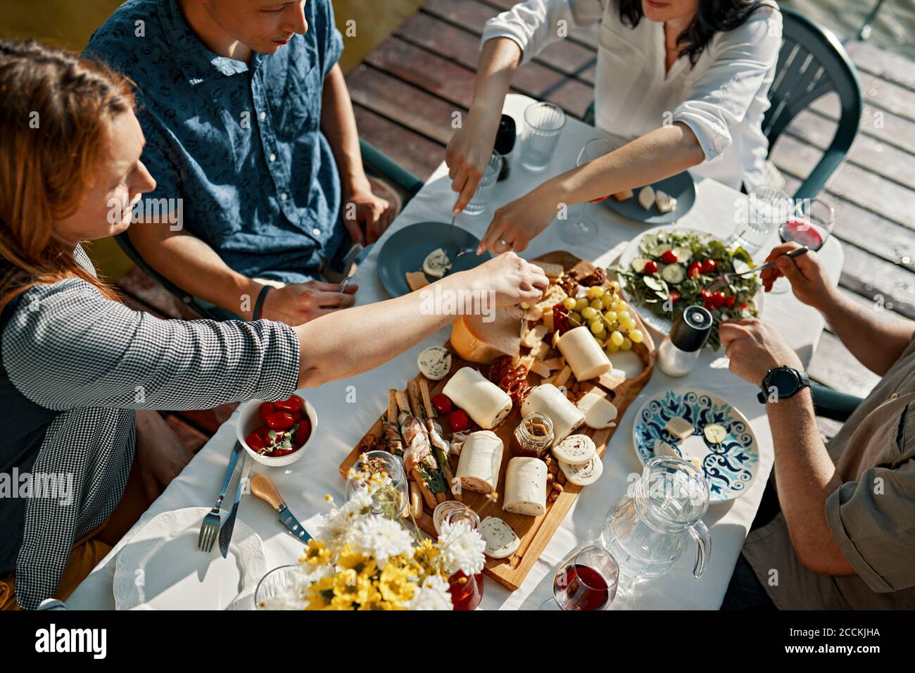 Friends having dinner with a cheese platter on jetty Stock Photo - Alamy