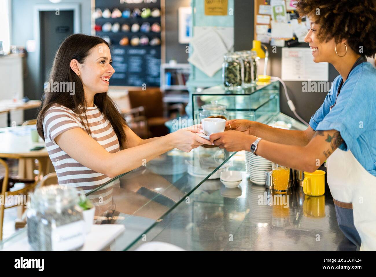 Happy owner selling coffee to young woman in cafe Stock Photo - Alamy