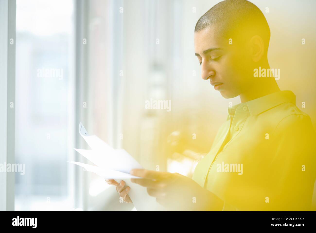 Businesswoman reading papers at the window in loft office Stock Photo ...