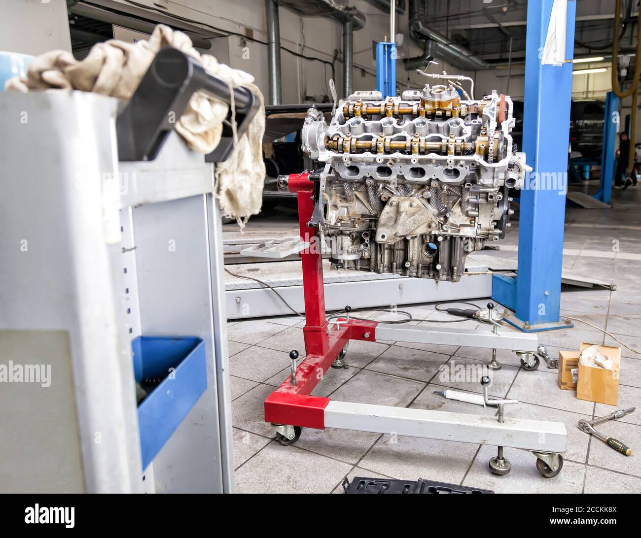An eight-cylinder iron engine removed from a car near a blue lift in ...
