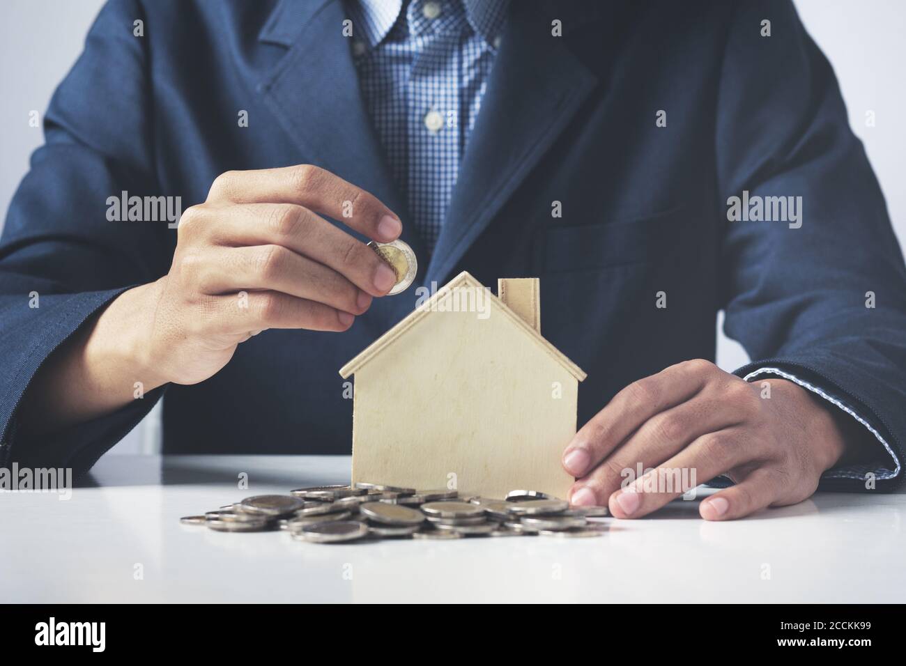Hand of Business man holding coin put in piggy bank with money stack ...