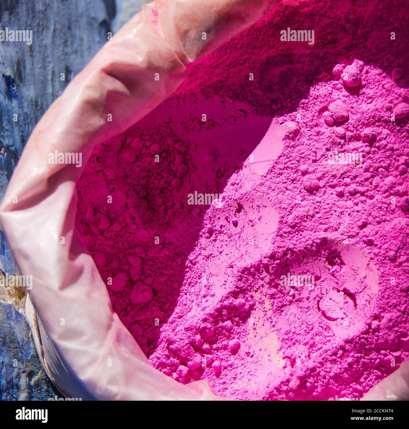 Powder of light red natural colorant in bag on the street in the blue ...