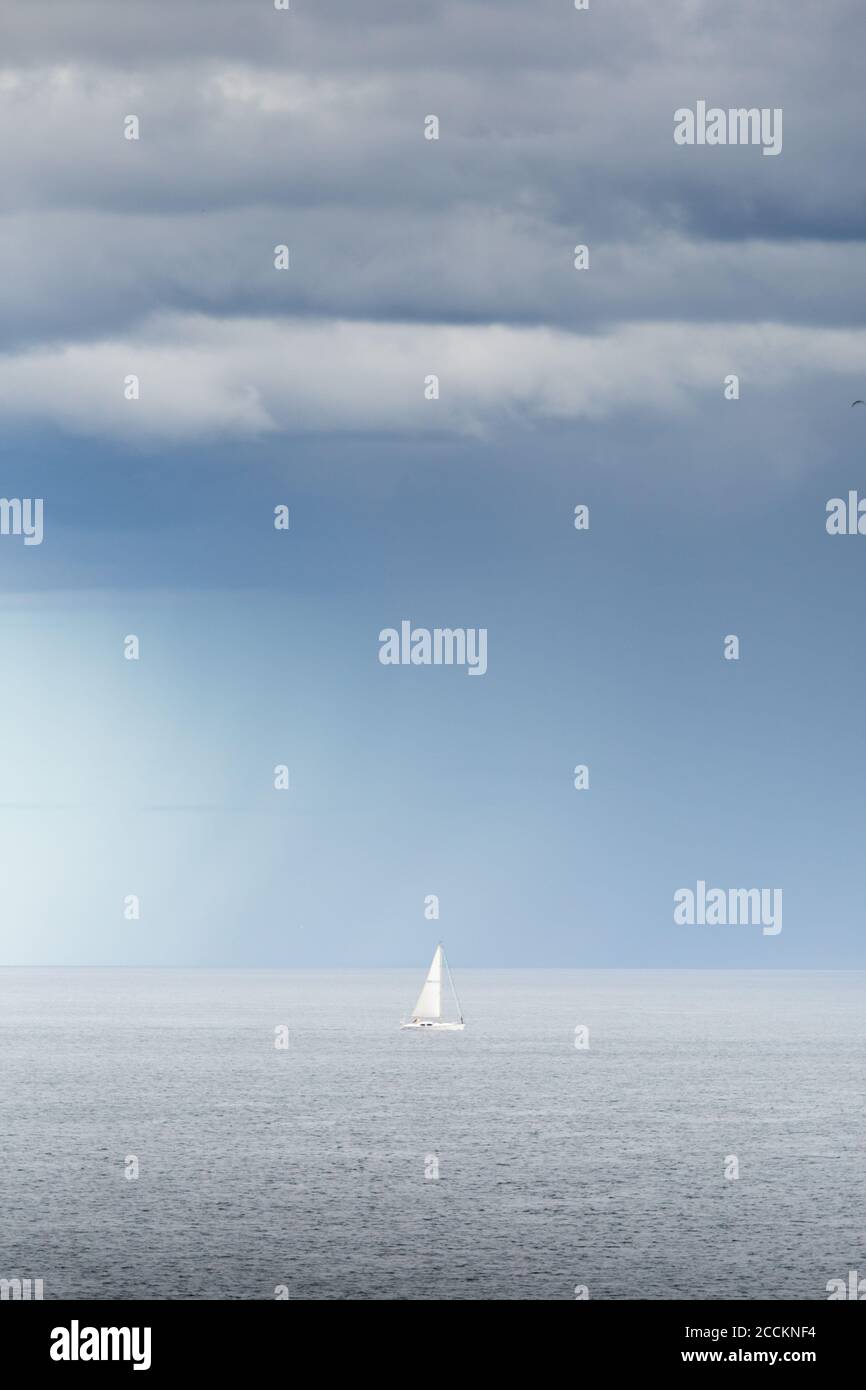Sail boat out at sea under a rain storm front cloud off the ...