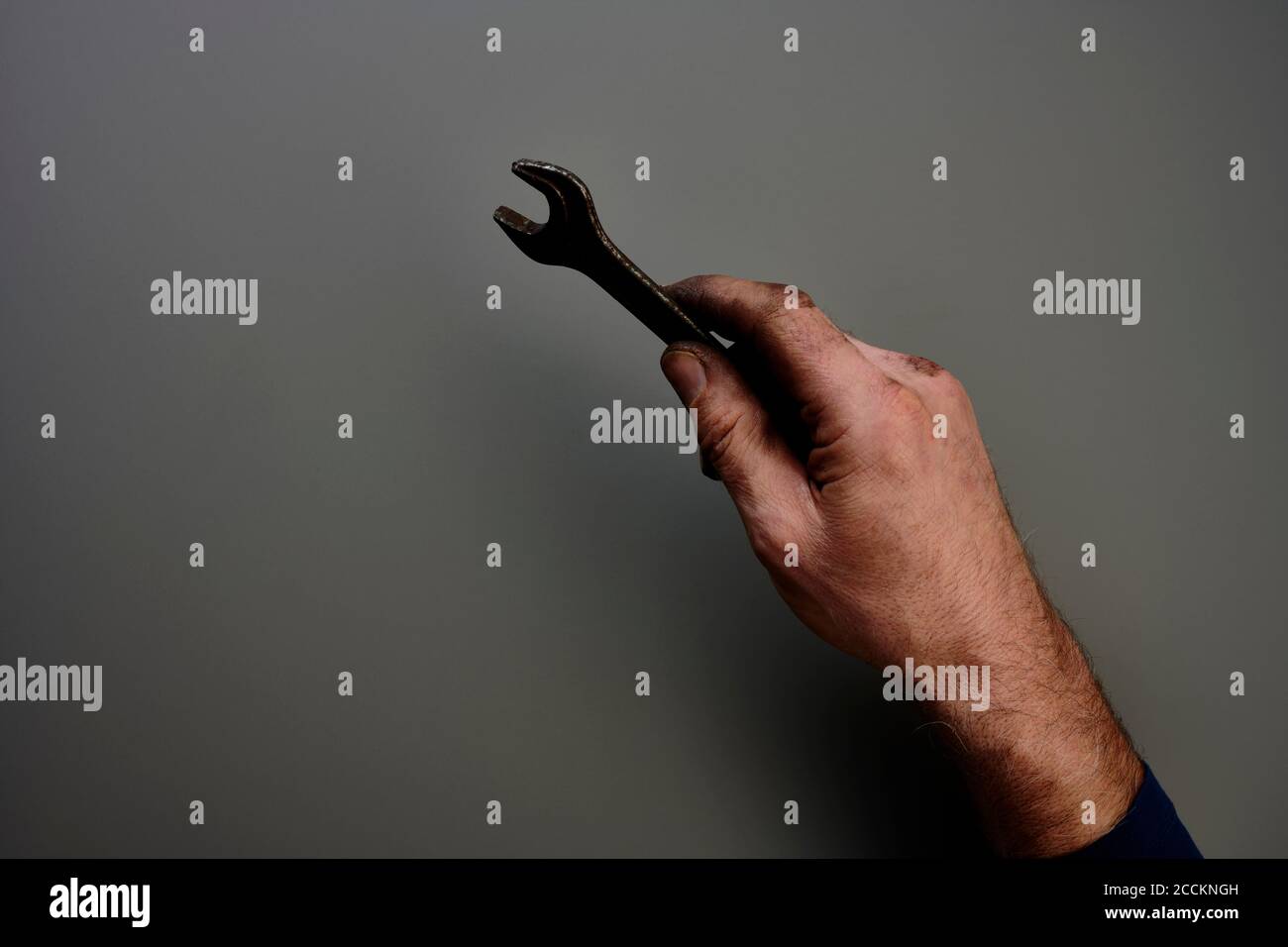 Top view of hand holding screw wrench in front of grey background Stock ...